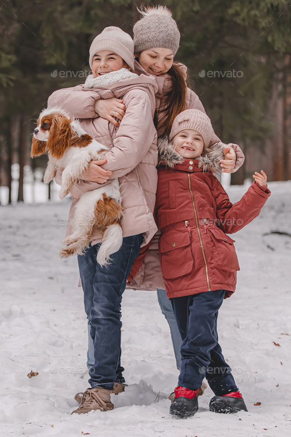 Mom and her daughters are playing in a snowy forest with their dog. Stock Photo by ...